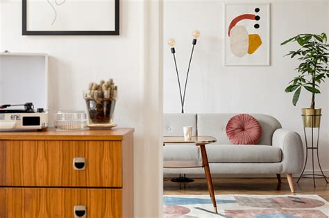 디자인 Commode와 거실의 복고풍 인테리어 커피 테이블 비닐 레코더 선인장과 모의 포스터 흰색 벽에 프레임 갈색 나무 마루와 식물이 있는 아늑한 객실입니다 0명에 대한