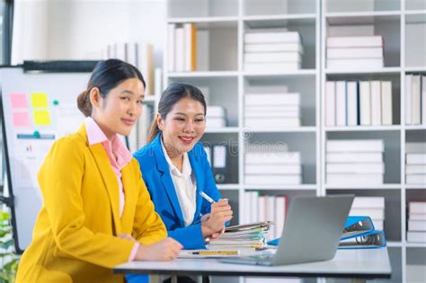 Two Asian Businesswomen Are Deeply Engaged In A Discussion About Data Analysis Work On A
