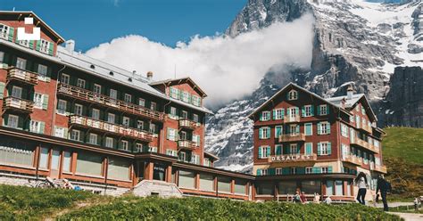 낮에는 푸른 하늘 아래 눈 덮인 산 근처의 갈색 콘크리트 건물 사진 Unsplash의 무료 라우터브루넨 이미지