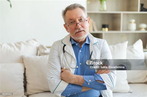 안경을 쓴 성숙한 선배 남자 의사가 병원에서 카메라를 보며 웃고 있다 일반 개업의 Gp 치료사 클리닉의 전문 의료 전문가 의료 개념입니다 70 79세에 대한 스톡 사진 및