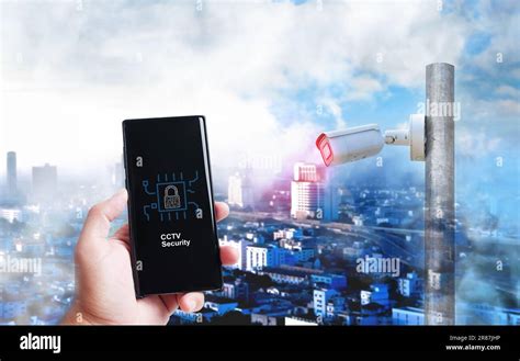 Smartphone Screen In Hand Displaying A Cyber Cctv Security Concept With A Cityscape In The