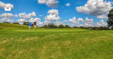 낮 동안 파란색과 흰색 흐린 하늘 아래 푸른 잔디밭에서 골프를 치는 사람들 사진 Unsplash의 무료 유스티스 이미지