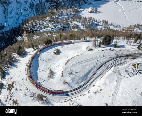 Aerial Image Of A Red Train Passing On The Rhaetian Railway Track With