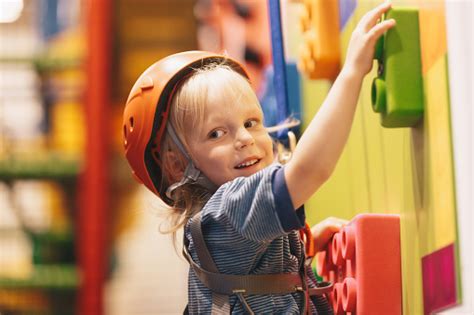 등반 벽에서 헬멧을 착용 한 학교 아이들 등반 로프에 매달려 볼더링 등반 센터에서 등반하는 행복한 소년 실내 암벽 등반에 대한