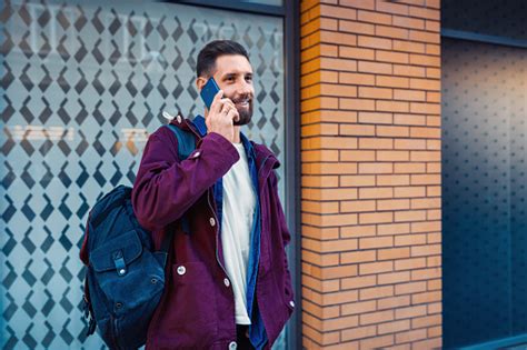 젊은 남자는 자신의 손에 스마트 폰으로 겨울 옷을 입고 거리에서 산책 가을에 대한 스톡 사진 및 기타 이미지 가을 거리