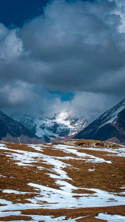극적인 하늘 아래 눈 덮인 아름다운 봉우리 · 무료 스톡 사진