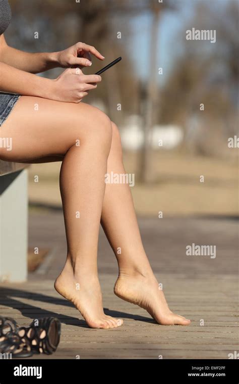 Woman Using A Smart Phone Relaxing In A Park Barefoot With An Unfocused