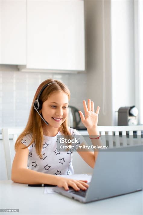 온라인 수업 전에 한 교사에게 손을 흔드는 랩톱 모니터 앞에 헤드셋을 탄 소녀 세로 사진 인터넷에 대한 스톡 사진 및 기타 이미지 인터넷 읽기 Brand Name