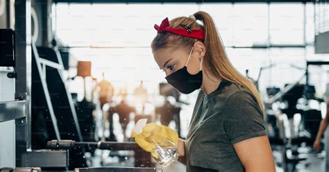 젊은 여성 노동자는 알코올 분무기와 천으로 청소를 소독하고 값비싼 피트니스 체육관 장비를 울고 있습니다 코로나 바이러스 글로벌 세계 전염병 및 건강 보호 안전 조치 사진