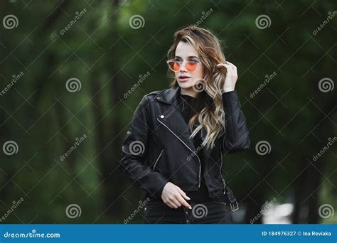 Молодая красивая девушка в кожаной куртке и модных солнечных очках ходить один на свежем воздухе