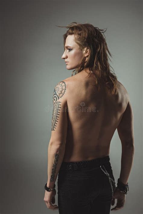 Shirtless Tattooed Man With Long Hair Posing In Black Jeans Stock Image