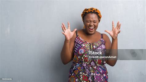 오렌지 입고 회색 그런 지 벽에 젊은 아프리카계 미국인 여자는 미친 축 하 머리 띠 무기와 성공을 위해 미친 제기 하 고 흥분 비명 눈을 폐쇄 우승자 개념 땋은 머리에 대한