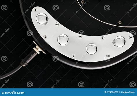 Cable Jack Connected To Black Electric Bass Guitar Input With Volume