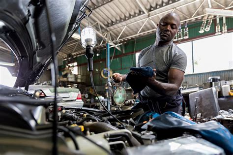 오일 품질을 확인하는 자동차 정비사 엔진 모터 자동차 변속기 및 유지 보수 장비 자동차 수리점의 자동차 정비사가 엔진을 점검하고 있습니다 45 49세에 대한 스톡 사진 및