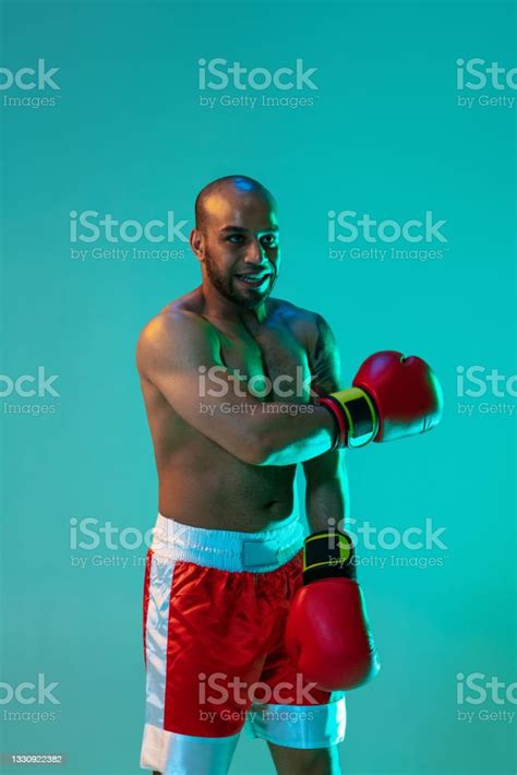 세로 이미지입니다 빨간 반바지와 장갑을 입은 프로 복서 한 명이 네온 라이트의 푸른 녹색 배경에서 포즈를 취하고 있습니다 25 29세에 대한 스톡 사진 및 기타 이미지