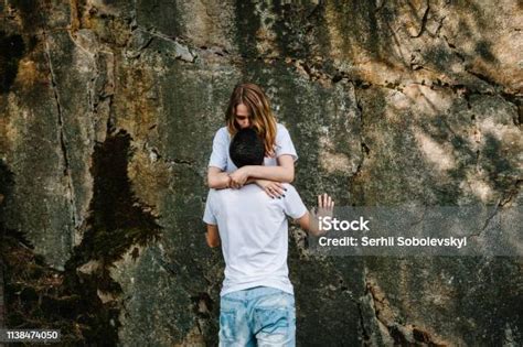 남자와 여자는 스탠드와 포옹 큰 바위 근처에 키스 돌 젊고 세련 되 고 사랑 하는 부부는 서로의 위 길이를 되돌아 봅니다 닫습니다 자연가을 측면 보기 2명에 대한 스톡 사진