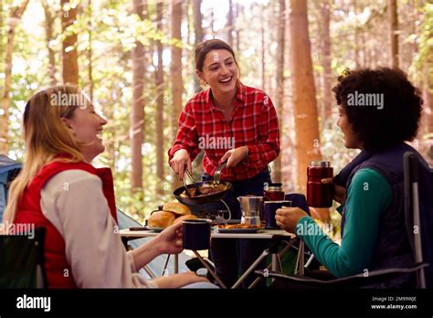 Group Of Female Friends On Camping Holiday In Forest Eating Meal