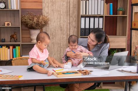 아름 다운 아시아 미혼모는 집에서 일하는 동안 사랑 스러운 아이들과 즐겁게 놀고 아이들은 어머니 작업 책상에서 재미있게 까꿍 놀이를하고 딸 개념을 가진 멀티 태스킹 젊은