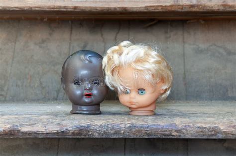 Heads Of One Black And One White Doll On Vintage Wooden Shelf Stock
