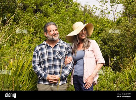 Happy Mature Couple Enjoying Nature Walk In Lush Green Garden Together