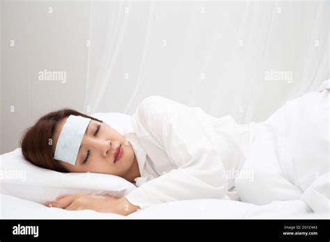 Young Asian Woman With High Fever While Sleeping On White Bed At Home