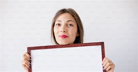 그녀의 손에 디스플레이를 들고 클로즈업 웃는 소녀는 그녀의 얼굴 근처에 프레임을 들고 카메라를 찾고 있습니다 장난스러운 텍스트 메시지의 개념 생일 사랑 및 휴일