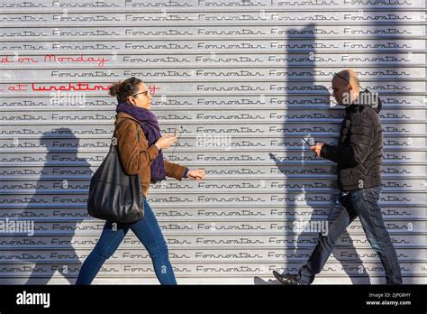 Two Passers By A Man And A Woman Pass Each Other In Front Of A Closed