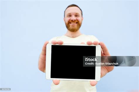 파란색 배경 클로즈업 텍스트에 고립 된 수염을 태블릿에 뭔가 보여주는 행복 한 잘생긴 젊은 남자 T 셔츠에 대한 스톡 사진 및 기타 이미지 Istock