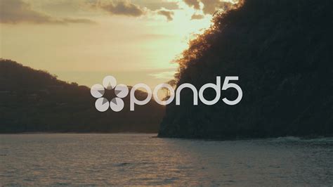 Passing An Island As The Sun Is Revealed Behind It Stock Footage Ad