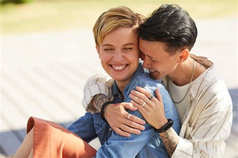 Premium Photo Two Young Happy Lesbians Sitting Outdoors Embracing And Laughing