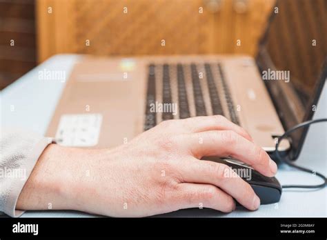 The Hands Of An Unknown Person Using A Laptop Moving The Cursor With The Mouse And Typing With