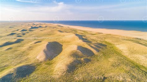 Aerial View Of Vast Coastal Sand Dunes And Ocean Under A Clear Sky