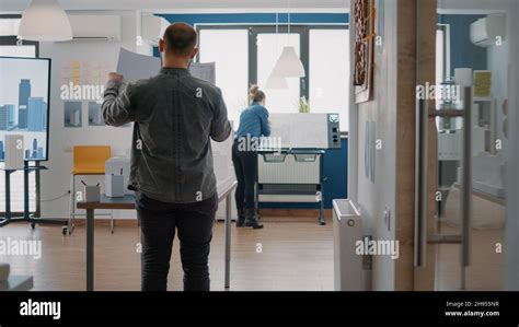 Man Architect Placing Blueprints Plan On Table To Design Building Model And Layout Using