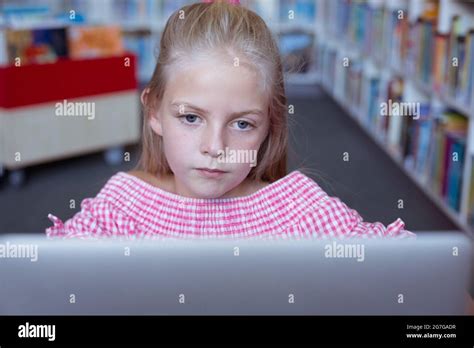Caucasian Schoolgirl At Desk In School Library Concentrating Using
