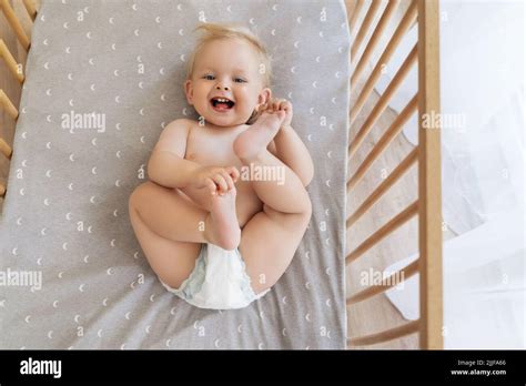 Upper View Portrait Of Happy Funny Playful Cute Baby In Diaper Lying On His Back Playing With