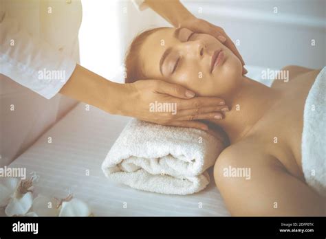 Beautiful Brunette Woman Enjoying Facial Massage With Closed Eyes In
