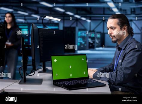 Engineer Using Green Screen Laptop To Do Maintenance In Server Hub