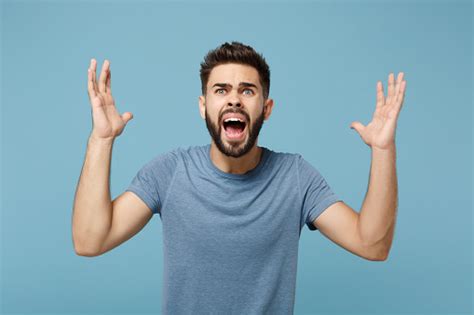 파란 배경 스튜디오 초상화에 고립 된 포즈 캐주얼 옷을 입은 젊은 화가 남자를 충격에 빠뜨렸습니다 사람들은 진지한 감정 라이프 스타일 개념 복사 공간을 모의합니다 위를