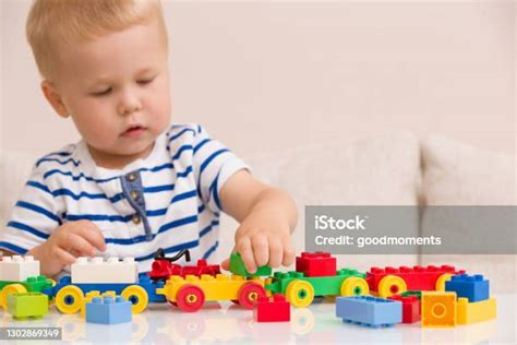테이블에서 화려한 플라스틱 벽돌을 가지고 노는 유아 소년 재미와 밝은 생성자 벽돌에서 구축 하는 유아 조기 학습 스트라이프 백그라운드 장난감 개발 가정 생활에 대한 스톡