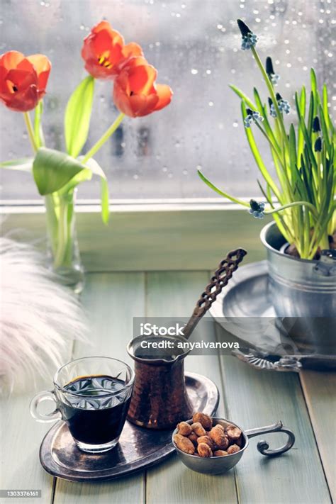 창틀에 꽃이 있는 전통 터키 구리 커피 냄비에 오리엔탈 커피 오렌지 튤립과 히아신스 화분이 있는 나무 창턱 봄에 비오는 날 아늑한 장면 Hygge 개념 0명에 대한 스톡