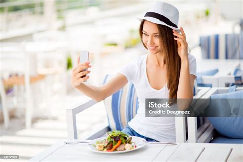 쾌활 한 숙 녀 열 공기 빛 테라스 야외는 여름에 점심을가지고 있다 그녀는 캐주얼에 데 샐러드와 복용 Selfie 그녀의 Pda와 모자를 고정 건강한 생활방식에 대한 스톡