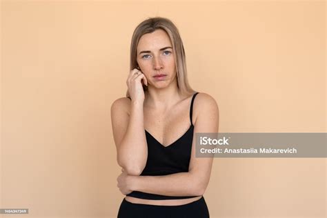 베이지색 배경 위에 서 있는 관계의 개인적인 문제에 대해 생각하는 슬픈 젊은 여성의 초상화 생각에 빠진 화가 난 소녀 외로움을 느낀다 우울하다 숙고 또는 애도 30 34세에