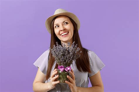 아름 다운 보라색 라벤더 꽃의 꽃다발을 들고 파란 드레스 밀 짚 모자에 행복 한 젊은 부드러운 여자의 밝은 동향 보라색 배경에 고립 국제 여성의 날 휴가 개념 건강관리와