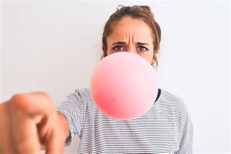 젊은 빨간 머리 여자 껌을 츄고 카메라와 당신에 게 손가락으로 가리키는 흰색 고립 된 배경 위에 머리 거품을 불고 손 기호 앞에서 긍정적이 고 자신감 제스처 가리키기에 대한