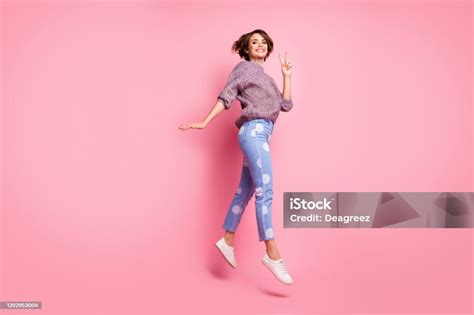 그녀의 전체 길이 몸 크기보기 그녀의 좋은 매력적인 사랑스러운 예쁜 쾌활한 쾌활한 쾌활한 기쁜 흥분 갈색 머리 소녀 점프 보여주는 V기호 는 분홍색 파스텔 색상 배경을 통해