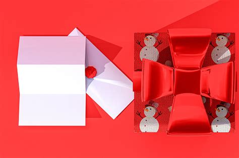 크리스마스 선물 상자는 밝은 밝은 빨간색 배경에 텍스트 또는 메시지를위한 공간으로 펼쳐진 크리스마스 봉투와 편지와 함께 빨간 리본 활로 묶여 있습니다 0명에 대한 스톡 사진