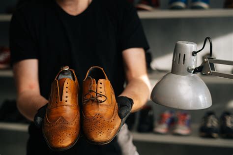 낡은 밝은 갈색 가죽 신발을 들고 검은 장갑을 낀 제화기술자 의 손의 클로즈업 프론트 뷰 가린 얼굴에 대한 스톡 사진 및 기타