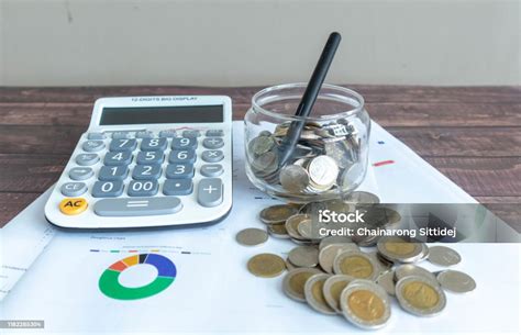 라인 그래프 파이 그래프 그리고 흰색 종이에 인쇄 된 다양한 색상의 그래프 계산기와 태국 바트 동전의 더미와 함께 나무 패턴