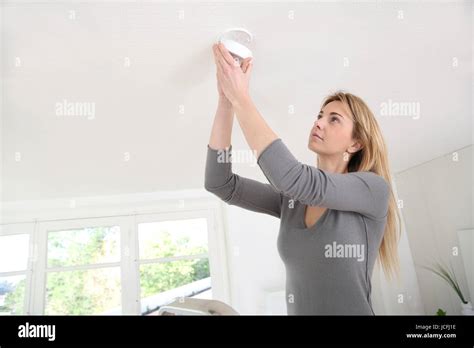 Woman Setting Up Fire Alarm Inside House Stock Photo Alamy