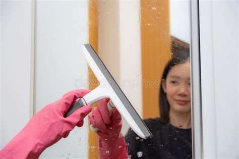 Hand In Pink Glove Using A Squeegee To Wipe A Wet Mirror Reflecting A